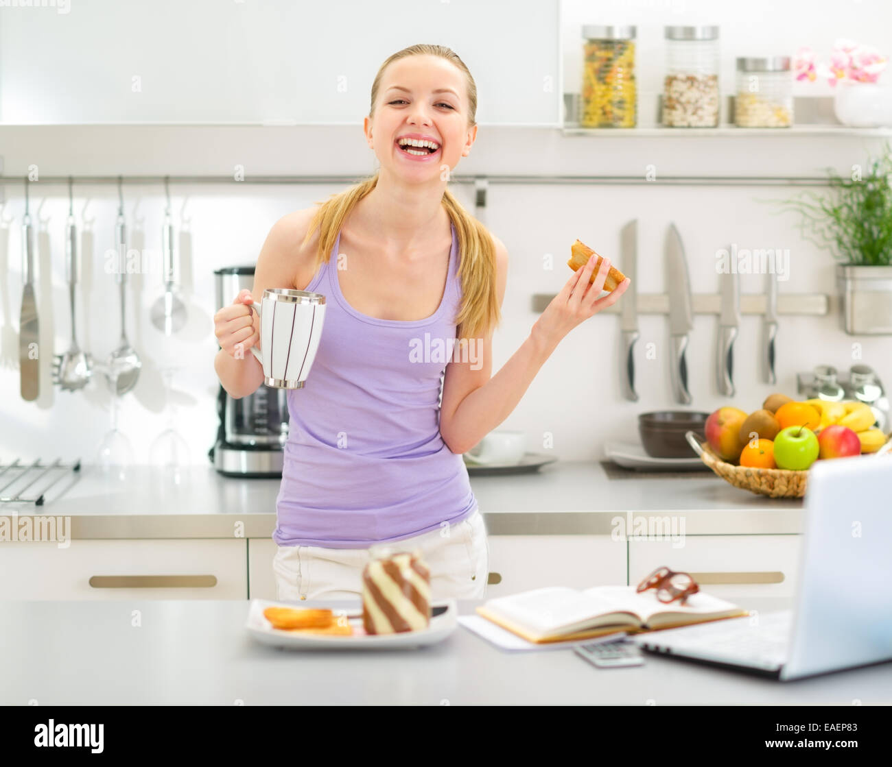 Happy teenager girl eating toast with chocolate cream in kitchen Stock ...