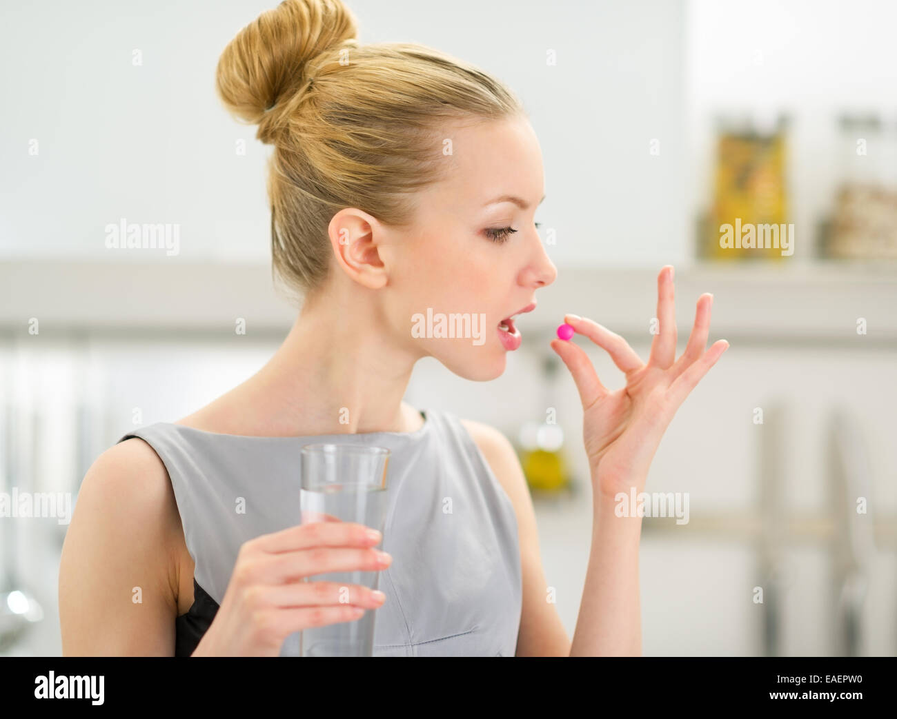 Young housewife taking pill in kitchen Stock Photo - Alamy