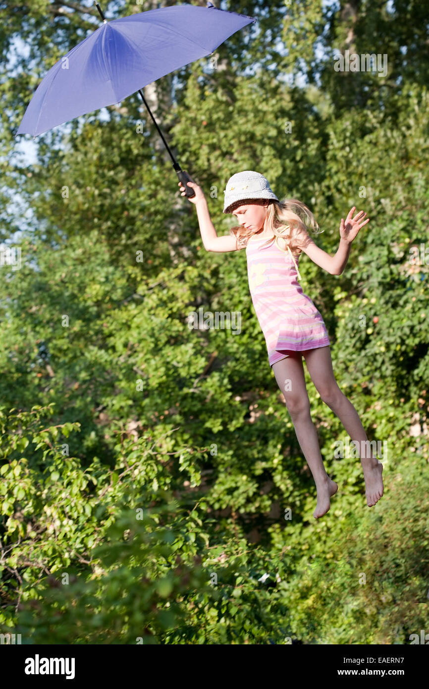 little girl flying with blue umbrella above summer garden trees Stock ...