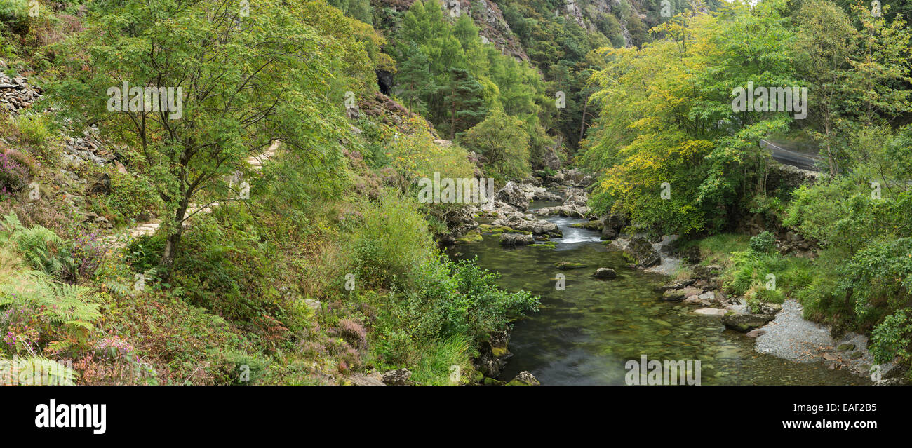 The road and a stone path line the river Glaslyn as it flows between ...