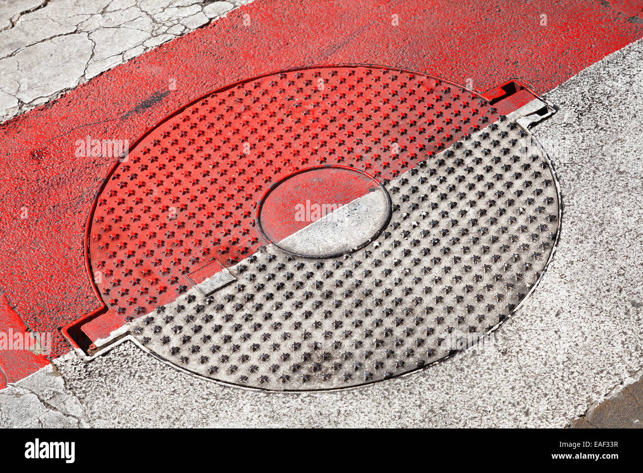 Closed round sewer manhole with stars pattern under red and white road ...