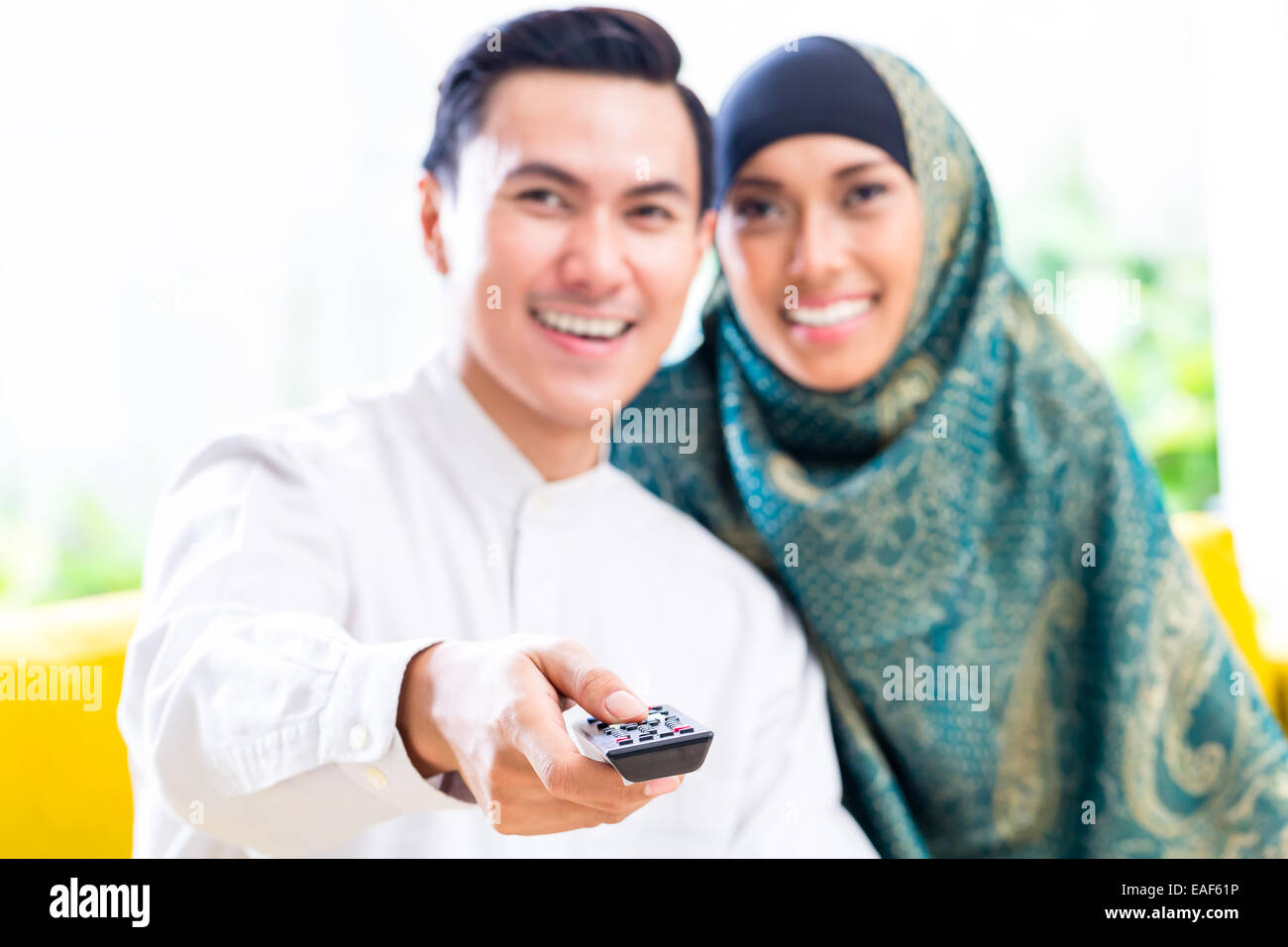 Asian Muslim man and woman watching television in living room Stock ...