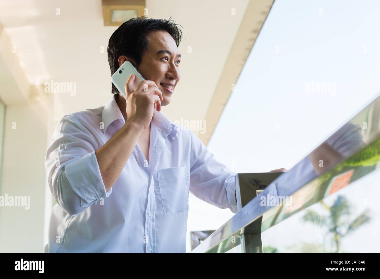 Asian man telephoning on home balcony with smartphone Stock Photo - Alamy