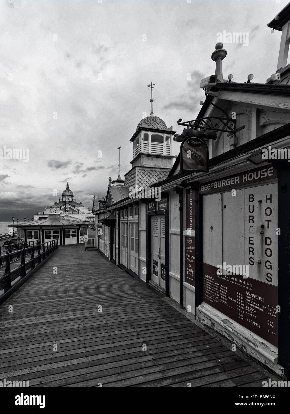 An old English pier with closed shops, black and white image ...