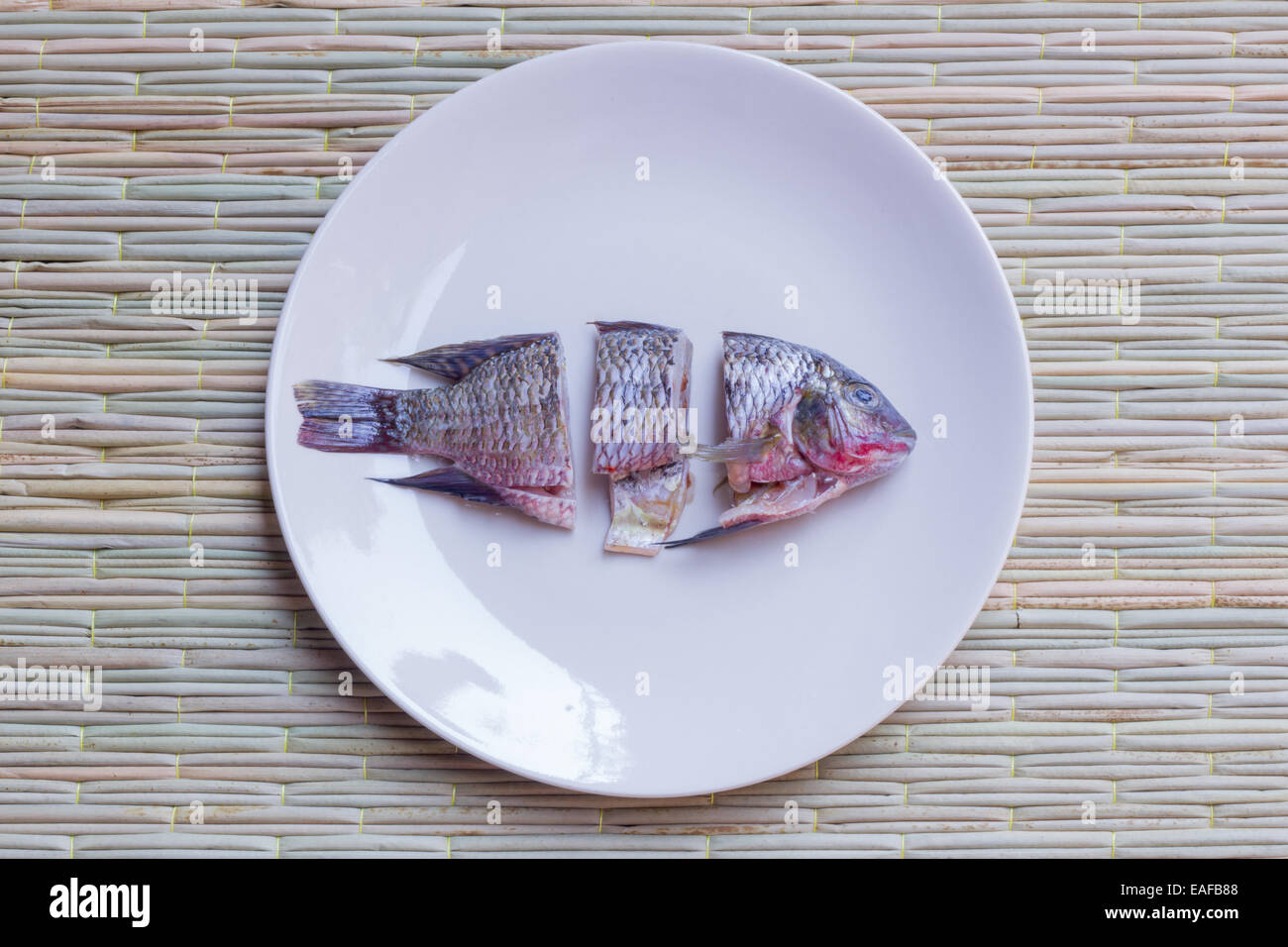 small choped fish in round dish, on a traditional mat Stock Photo - Alamy