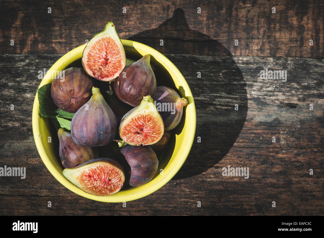 Figs in yellow bowl on wood Stock Photo - Alamy