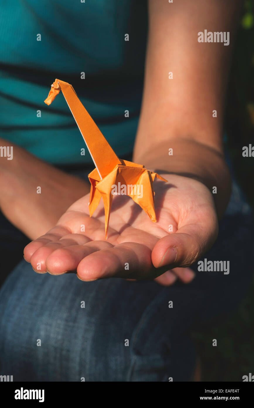 Origami orange color giraffe on hand Stock Photo - Alamy