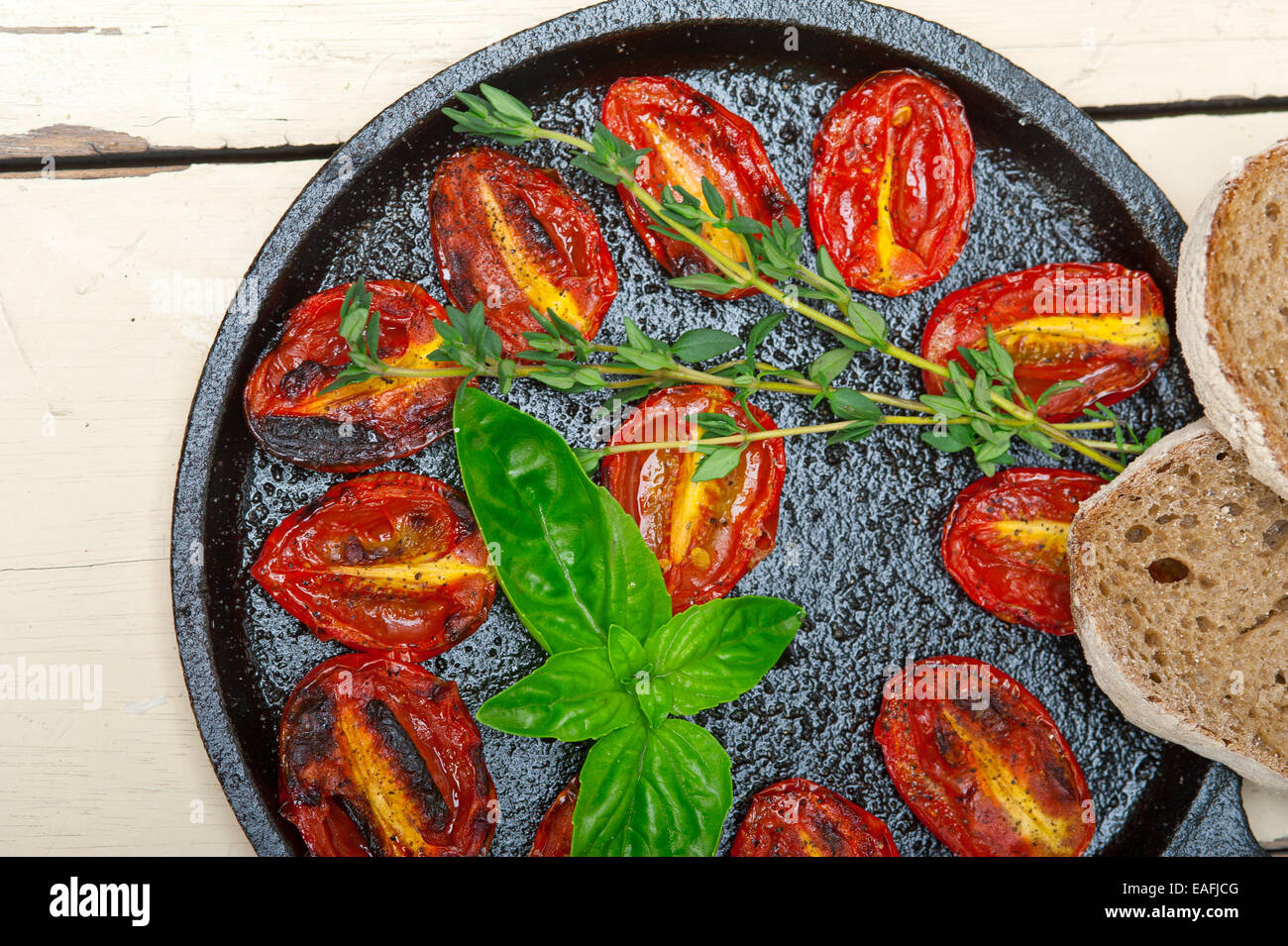 oven baked cherry tomatoes with basil and thyme on a cast iron skillet ...