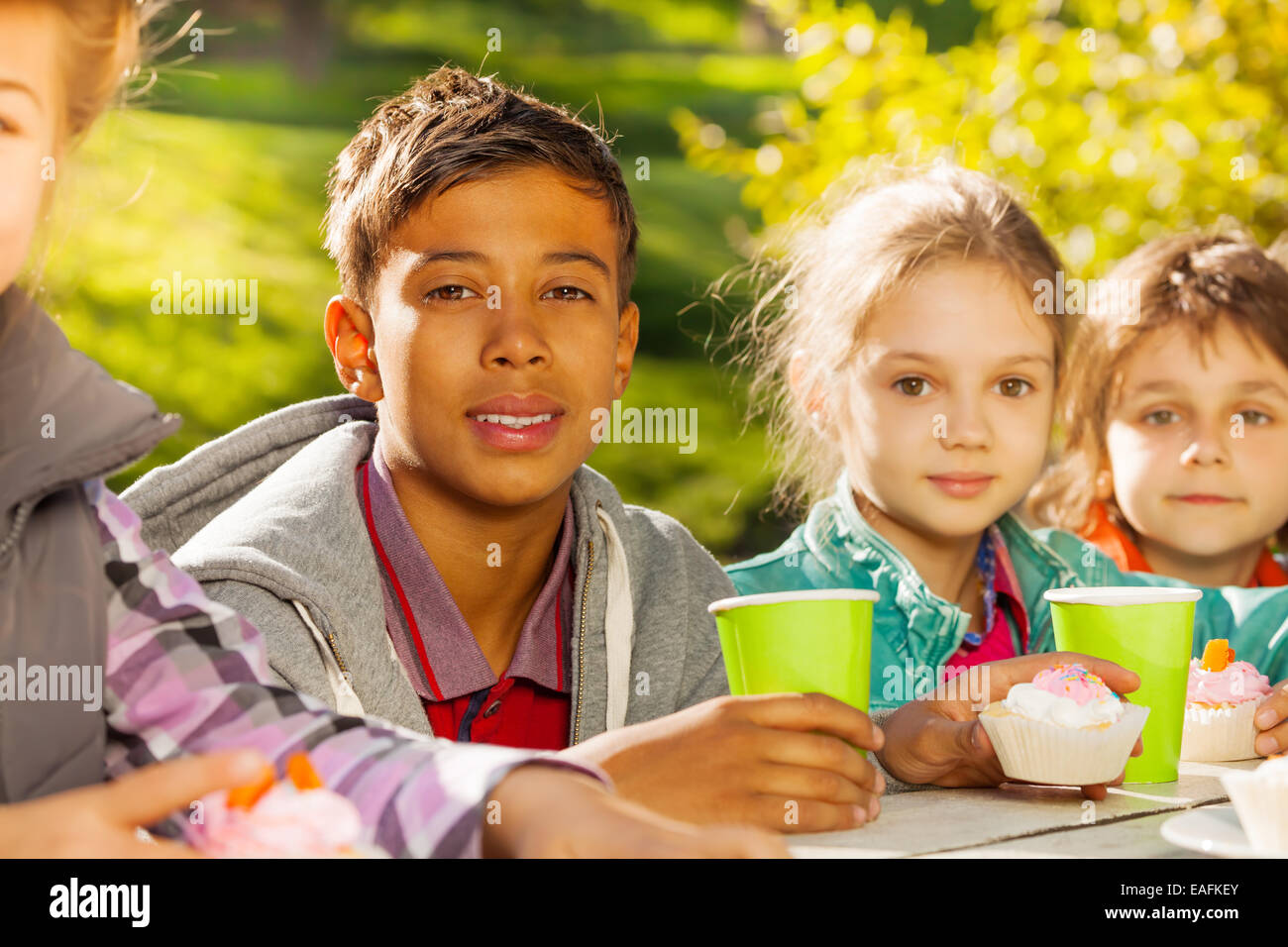 International children sit with cups outside Stock Photo - Alamy
