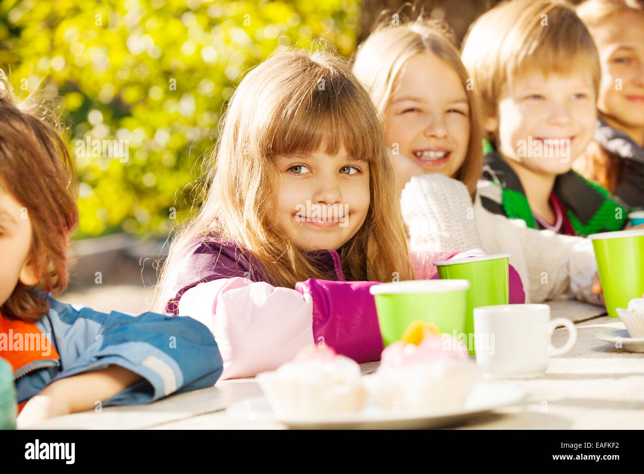 Happy children with tea cups sitting outside Stock Photo - Alamy