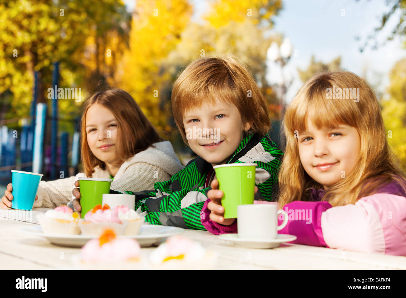 Happy kids with tea cups sitting outside Stock Photo - Alamy