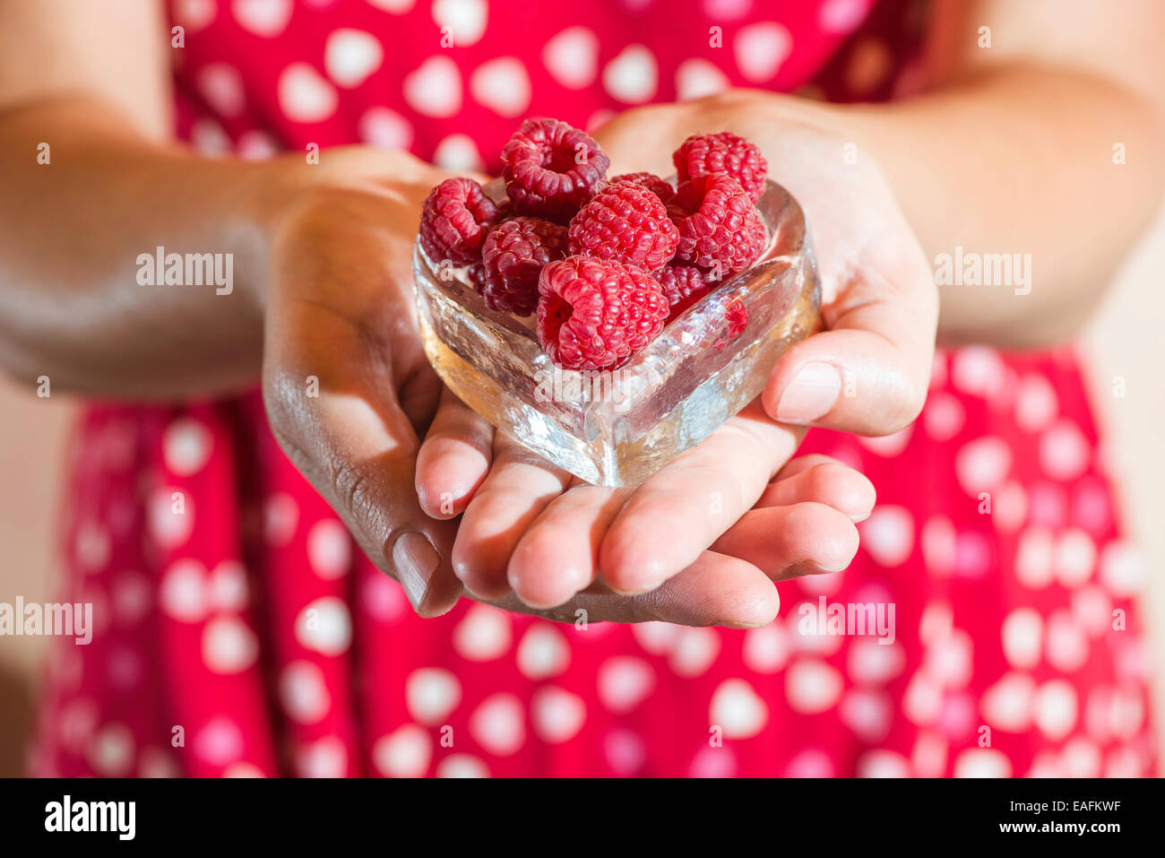 Woman in red dress holding a cup of raspberries Stock Photo - Alamy