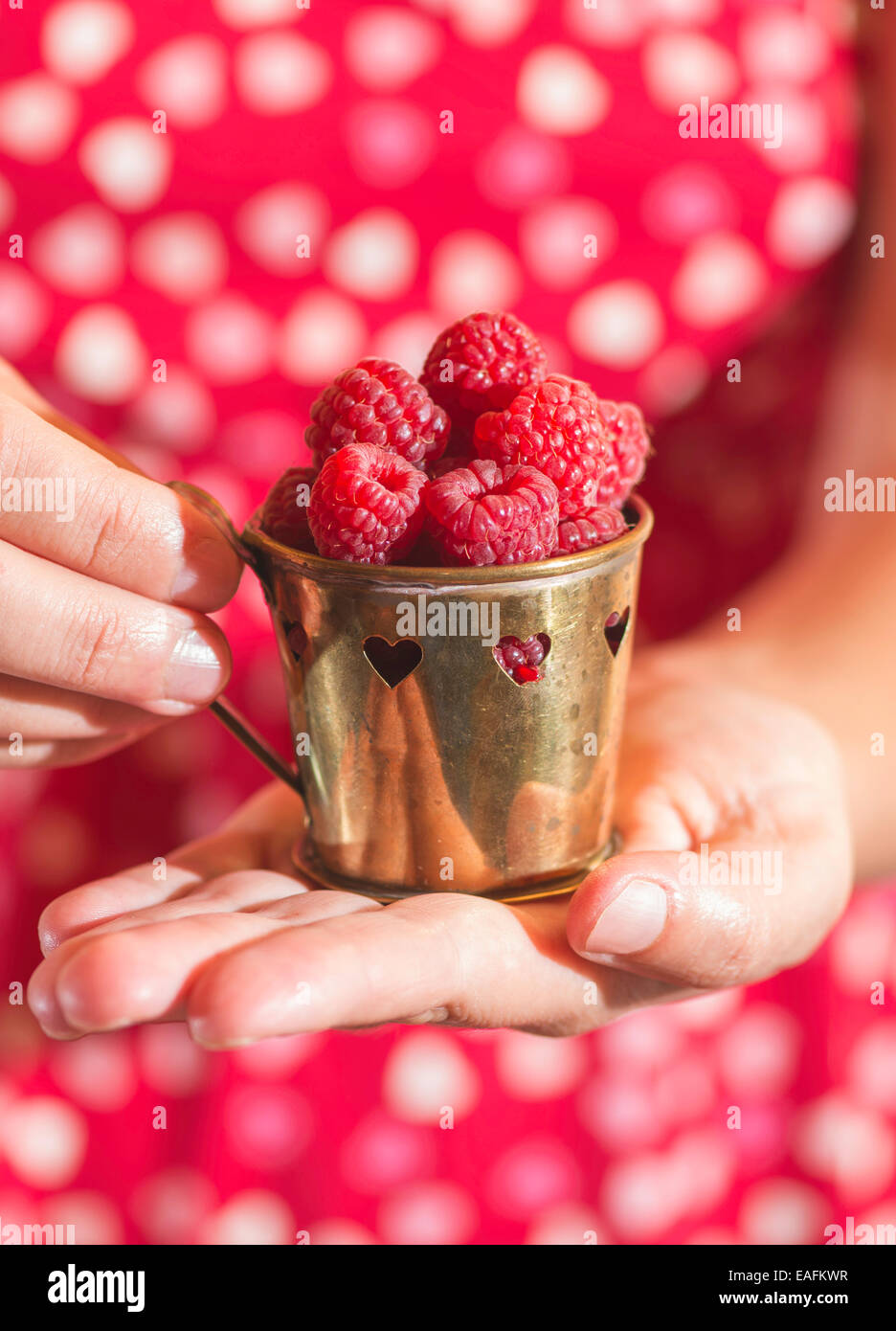 Woman in red dress holding a cup of raspberries Stock Photo - Alamy