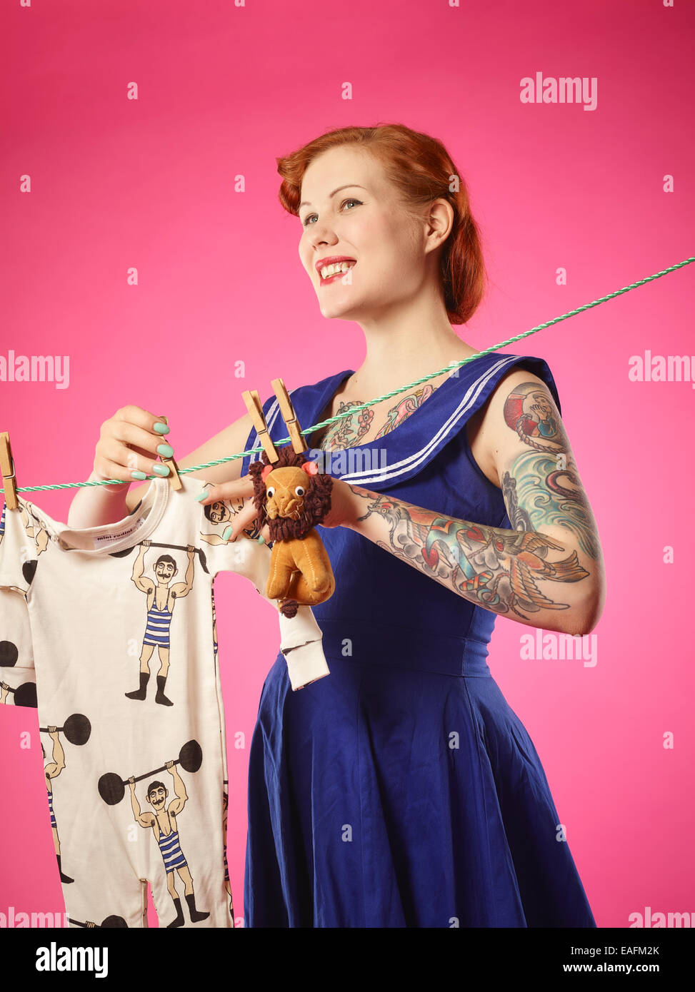 The expectant woman hang up baby clothes to clothesline Stock Photo - Alamy