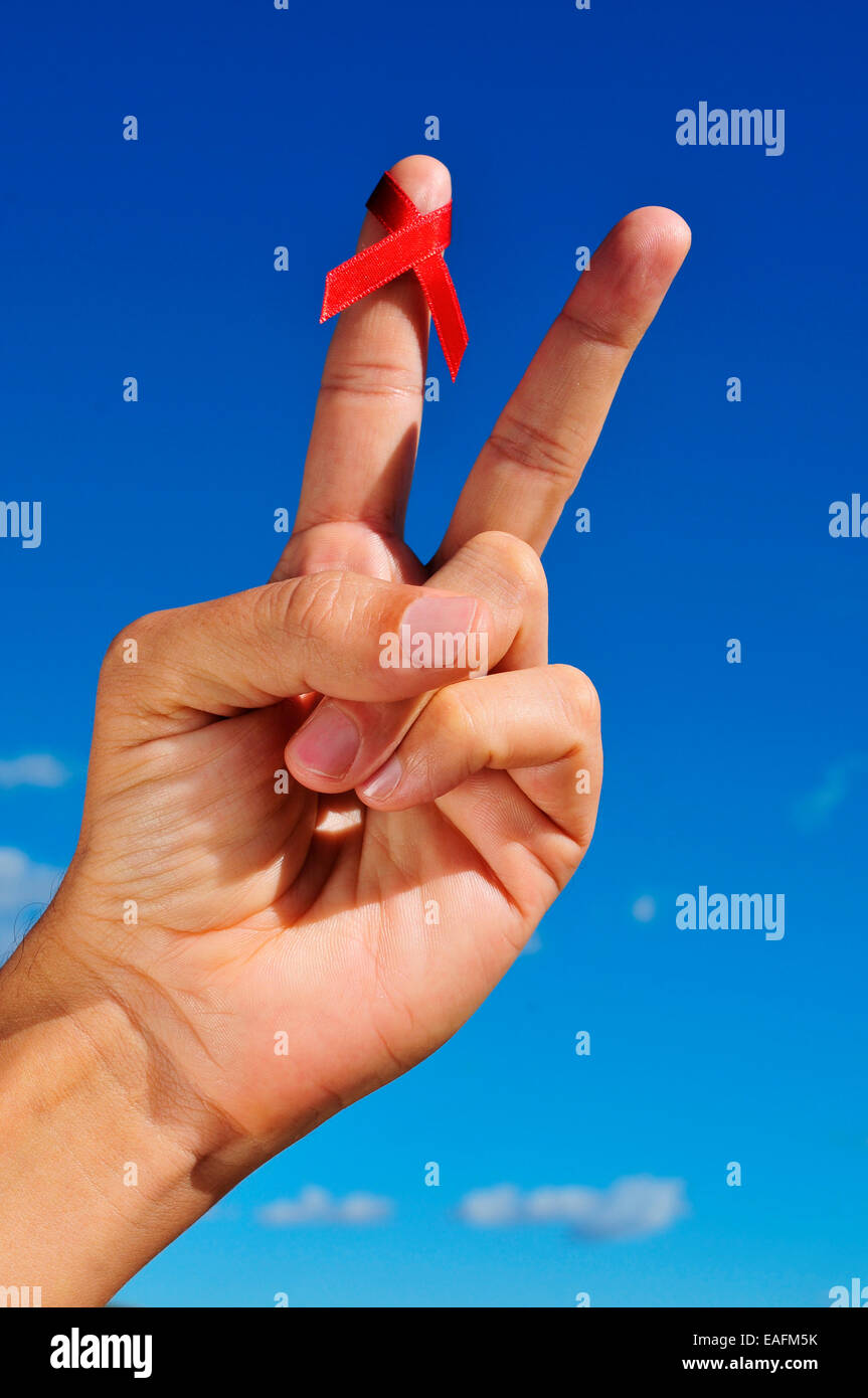 a man hand doing the V sign with a red awareness ribbon for the fight ...