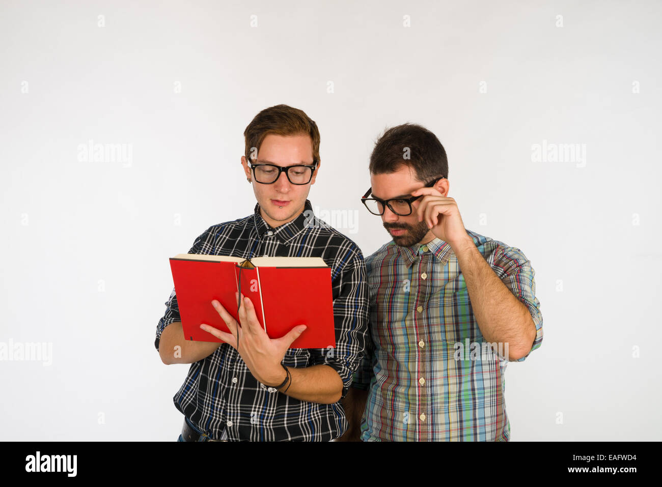 Two nerd looking young guys concentrated on a book Stock Photo - Alamy