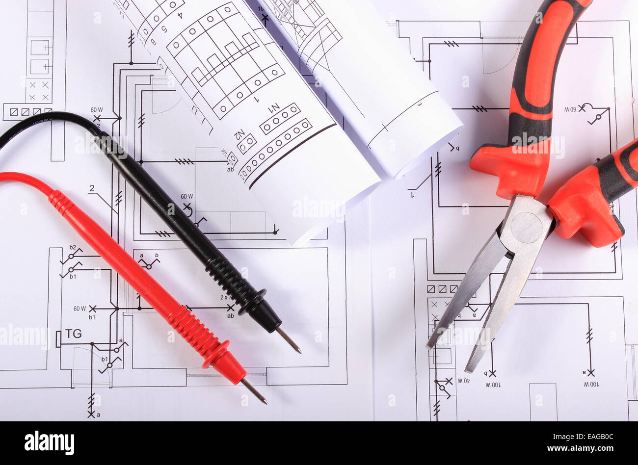 Rolls of electrical diagrams, cables of multimeter and metal pliers ...