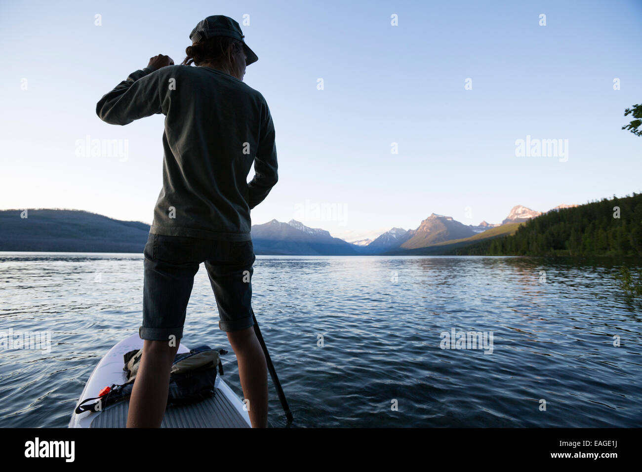 A woman stand up paddle boards (SUP) on Lake McDonald in Glacier ...