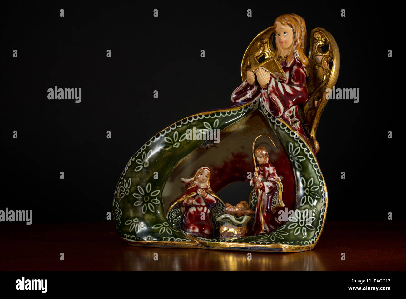Nice ceramic crib on wood table and black background, with Angel on top ...