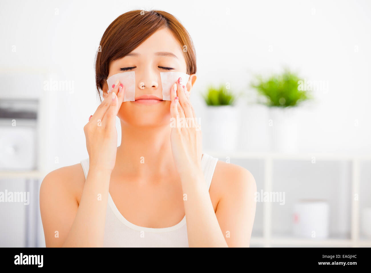 Beautiful young woman cleaning her face with cotton Stock Photo - Alamy