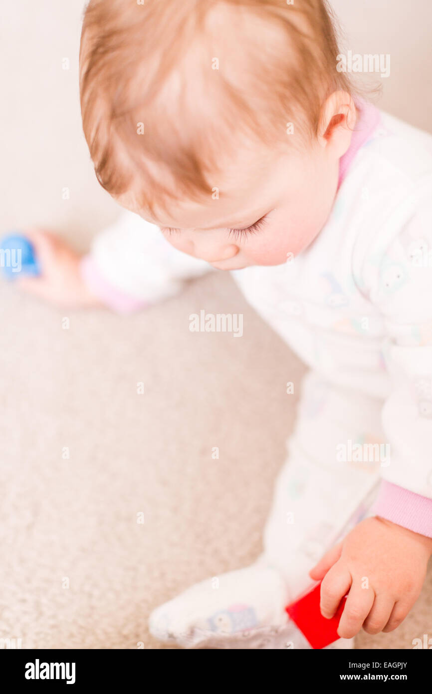 Cute baby girl playing with cubes on the floor Stock Photo - Alamy