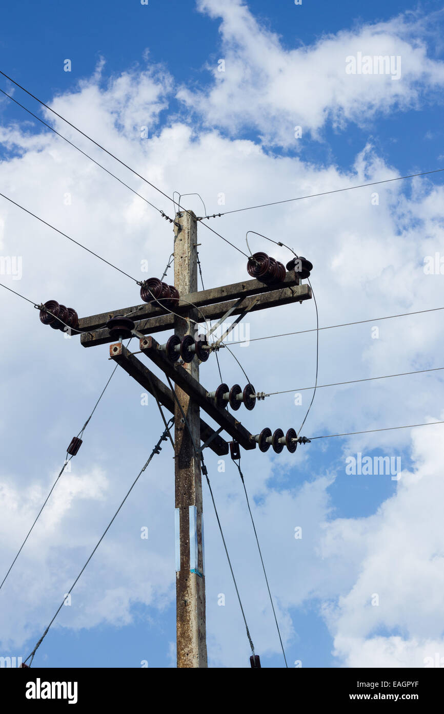 electrical post by the road with power line cables, against blue sky ...