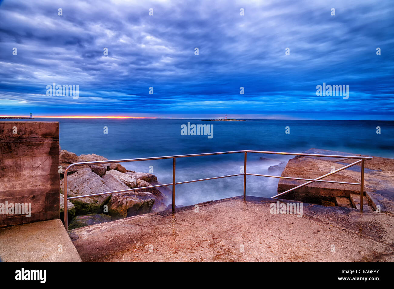 Sunset on breakwater with stairs on the Mediterranean sea with red ...