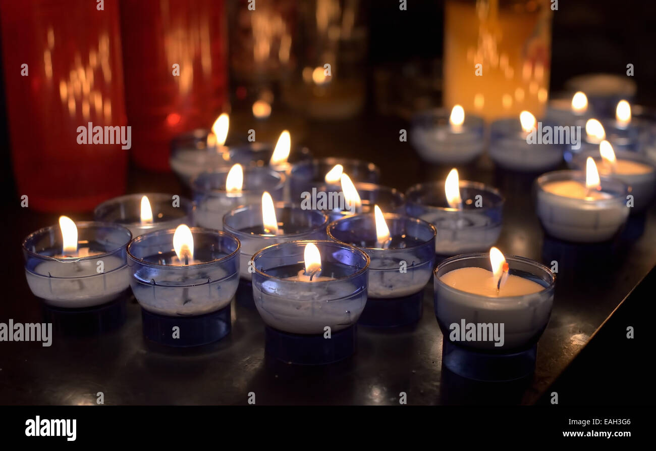 Different colors firing candles in catholic church on dark background ...