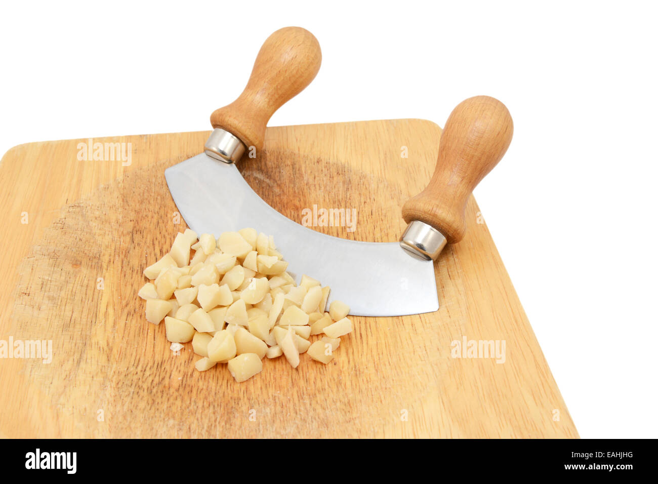 Coarsely chopped macadamia nuts with a rocking knife on a wooden ...