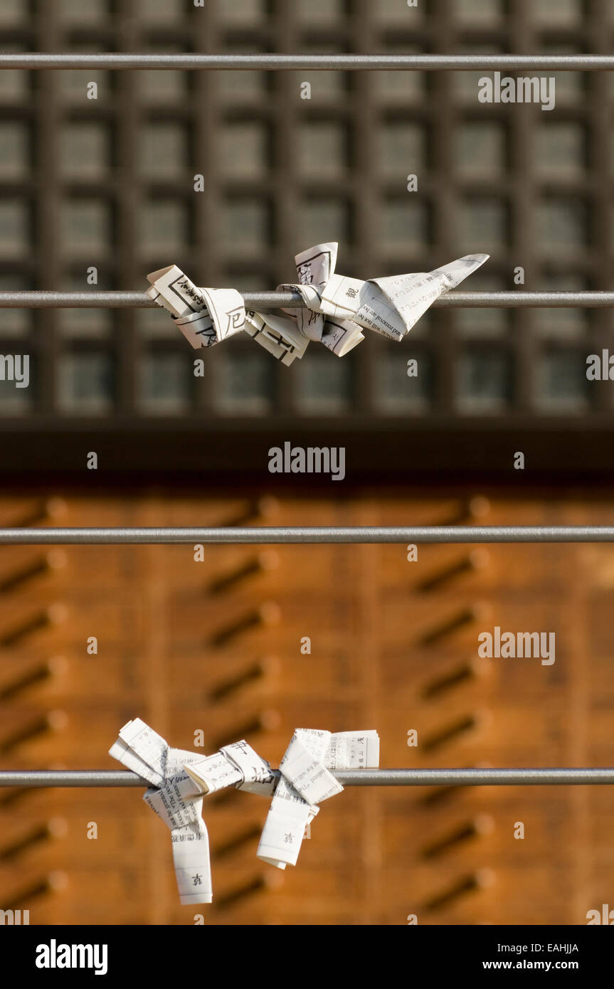 Tying Buddhist omikuji, fortunes written on slips of paper, to a rack ...