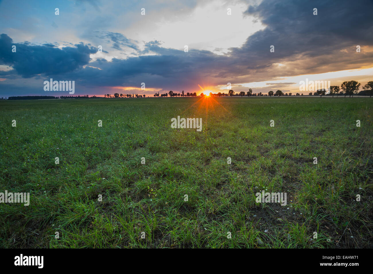 Beautiful sunset over field. Orange sky and illuminated clouds Stock ...