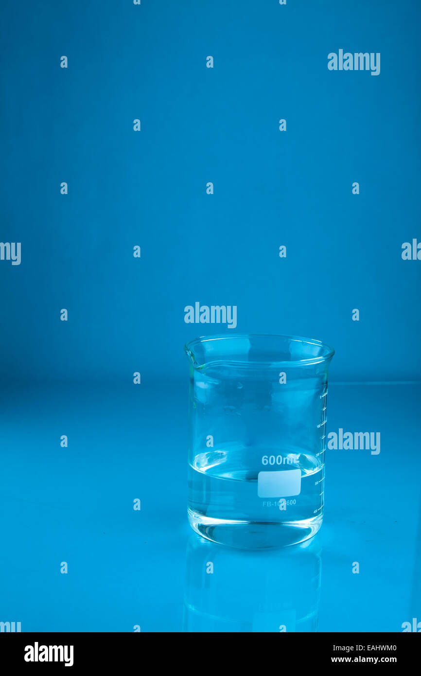 A beaker of water on a blue background Stock Photo - Alamy