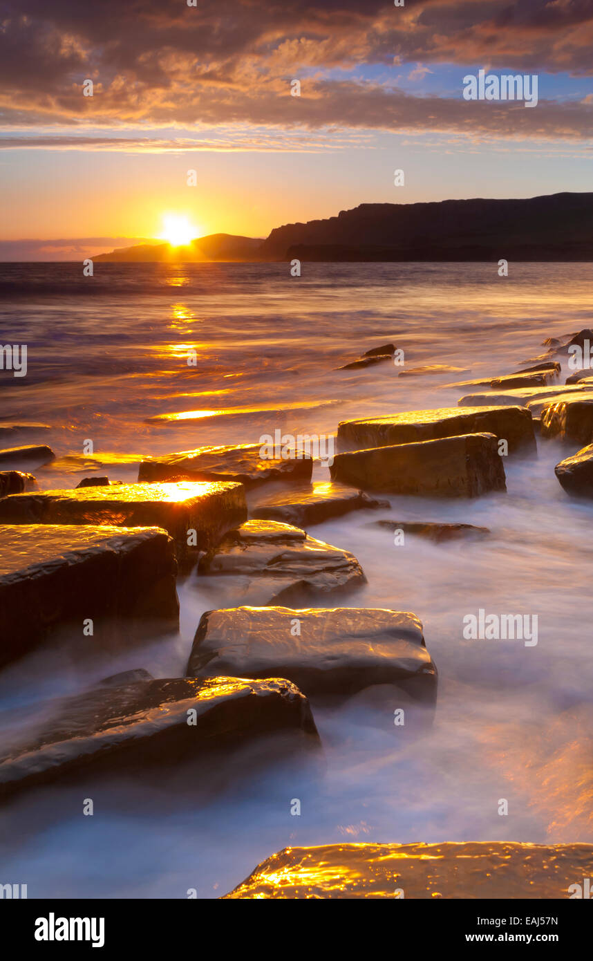 The sun sets on the beautiful Dorset coastline illuminating glistening ...