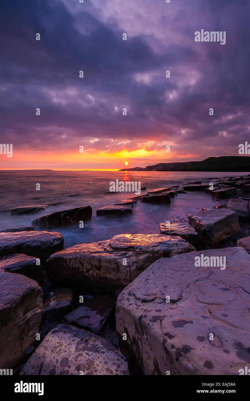 The sun sets on the beautiful Dorset coastline illuminating glistening ...