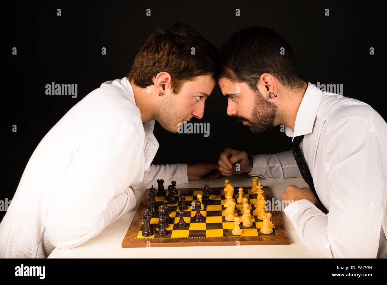 Two guys in their 20s clashing over a chess board Stock Photo - Alamy