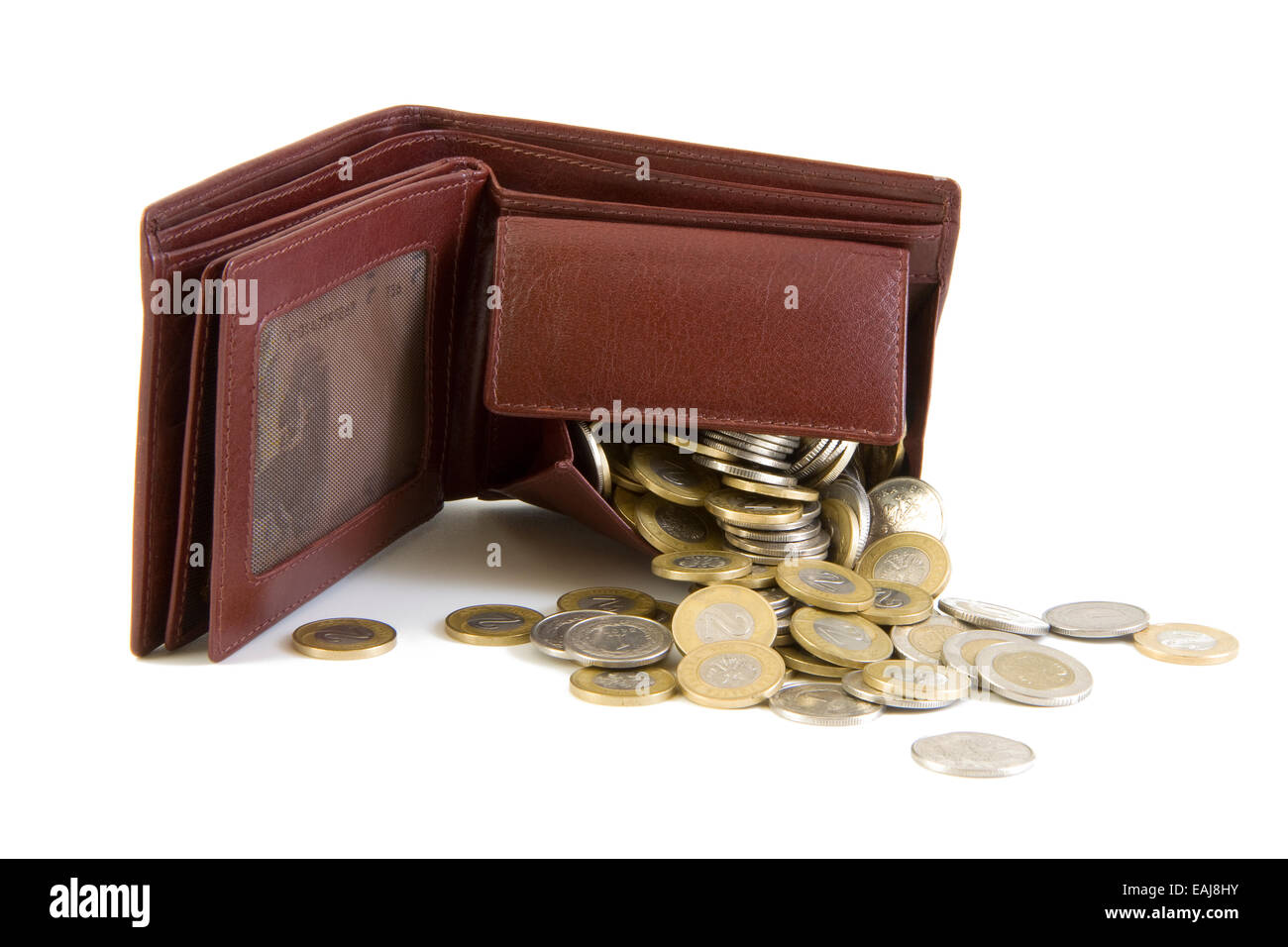 Coins spilling from a brown leather wallet, isolated on white ...