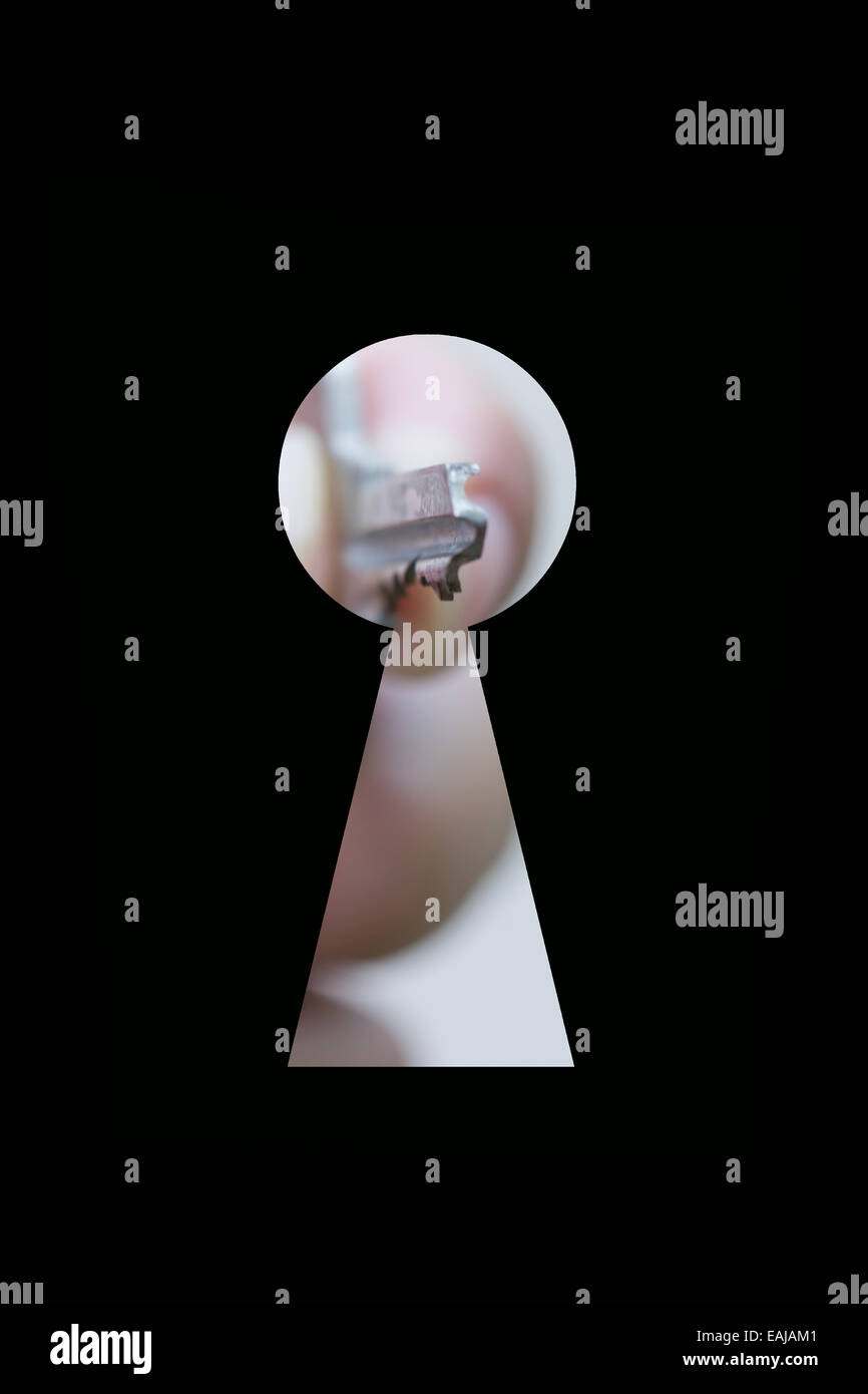 Key in hand prepares to open in keyhole, close up, isolated on black ...