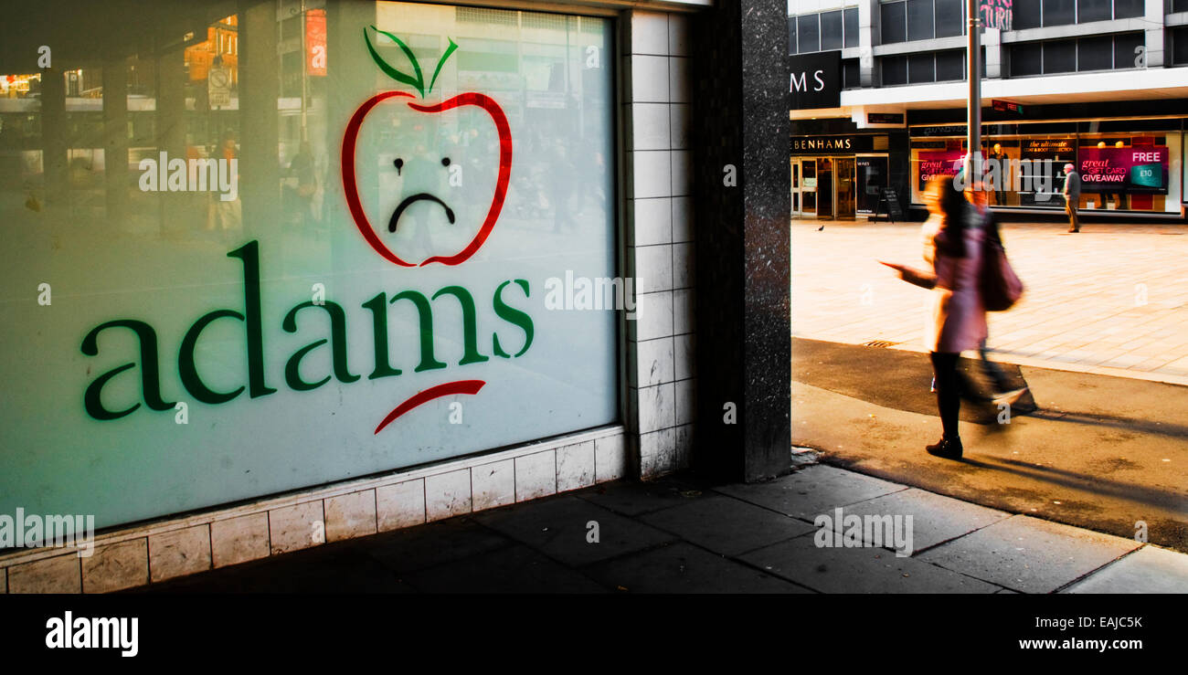 A woman walks past graffiti of a closed branch of Adams children's wear ...