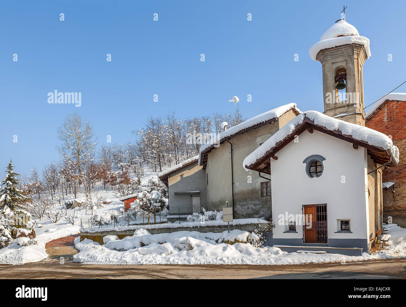 Small rural chapel covered with white snow under blue sky in sunny ...