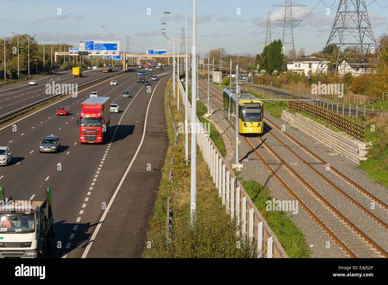 Metrolink tram alongside the M60 motorway, on the Airport Line ...