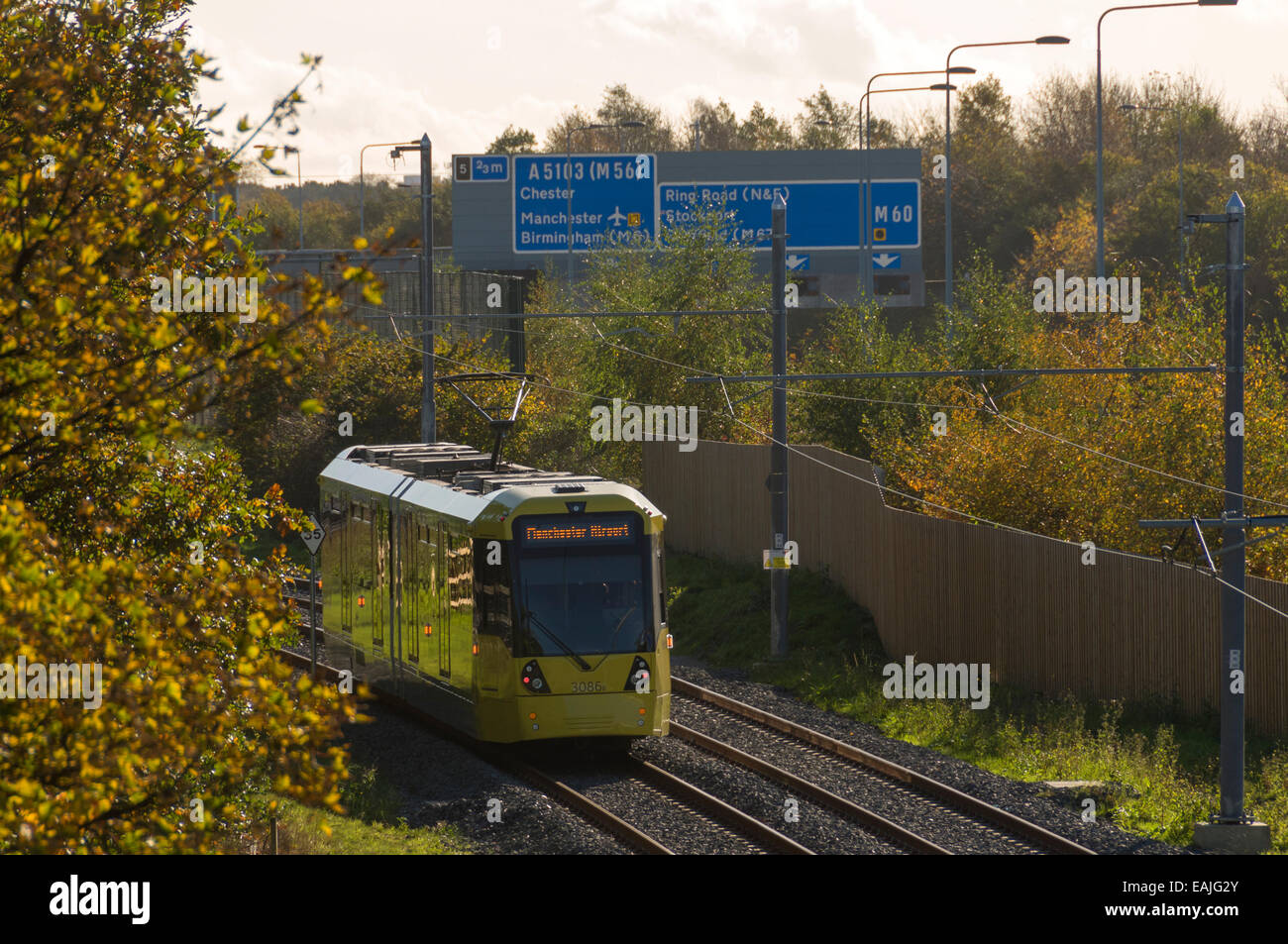 Metrolink tram alongside the M60 motorway, on the Airport Line ...