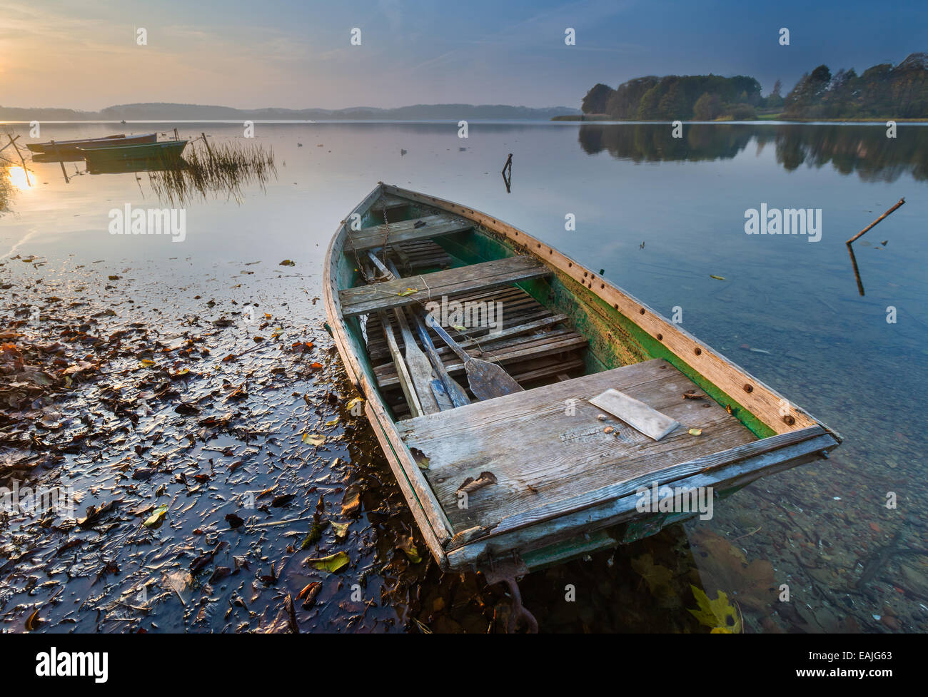 Boat on calm lake at sunset Stock Photo - Alamy