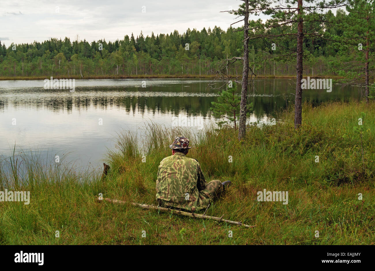 The fisherman with a fishing-rod on the forest lake coast Stock Photo ...