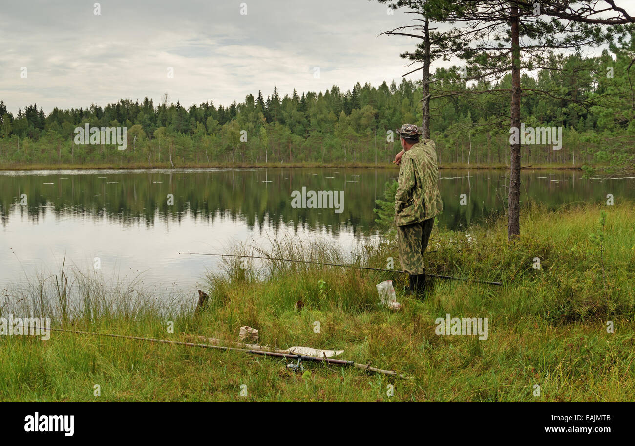 The fisherman with a fishing-rod on the forest lake coast Stock Photo ...