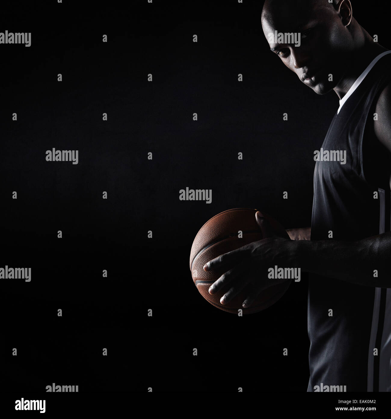Studio shot of strong young man holding basketball looking at camera ...