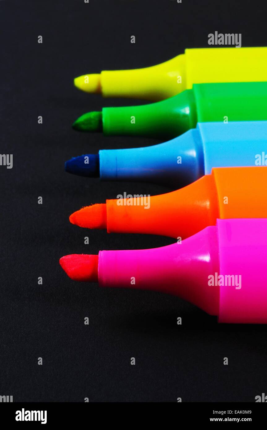 Highlighter pens with caps removed against a black background Stock ...