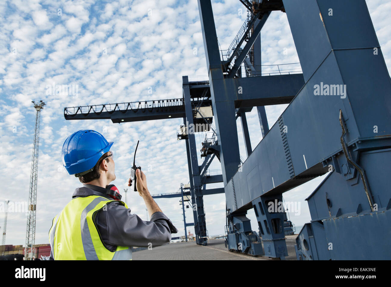 Worker using walkie-talkie under cargo crane Stock Photo - Alamy
