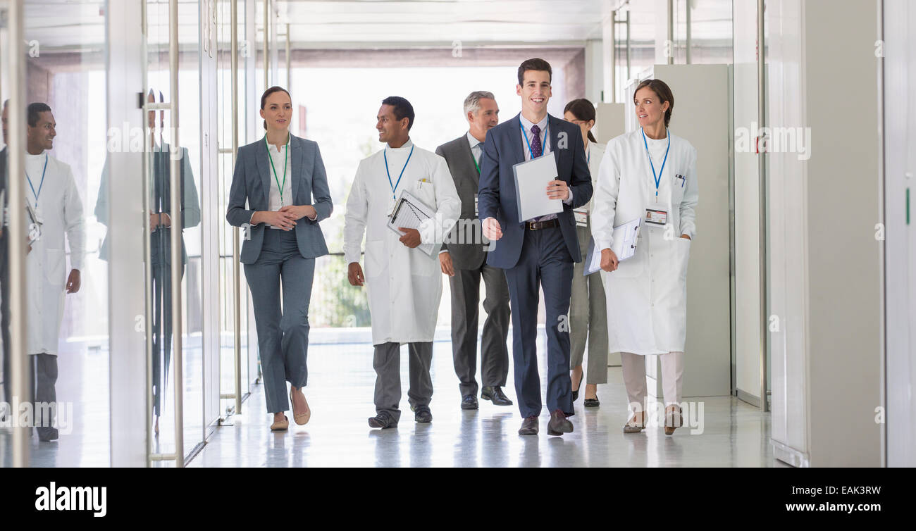 Scientists and business people walking in hallway Stock Photo - Alamy