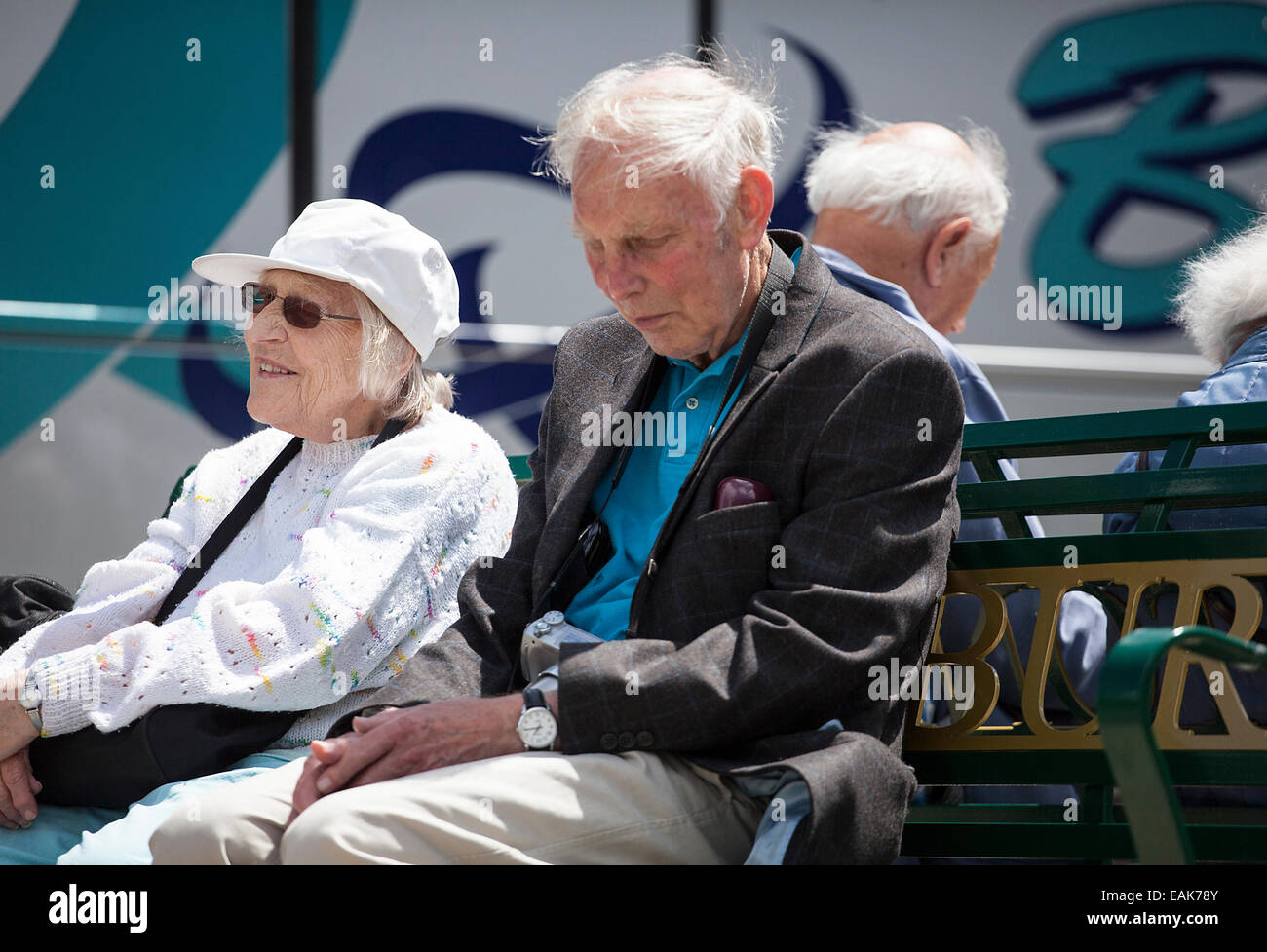 A retired white European couple age 70 plus sitting on a park bench ...