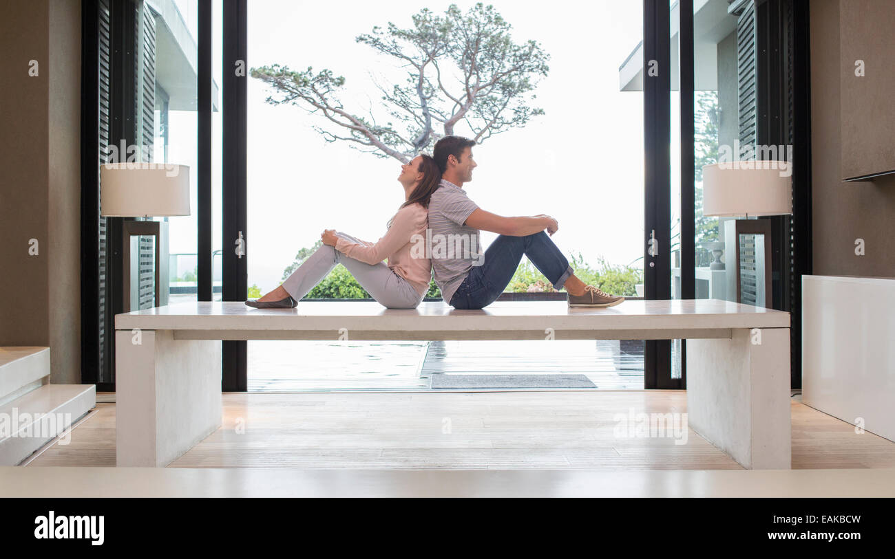 Couple sitting back to back on table Stock Photo - Alamy